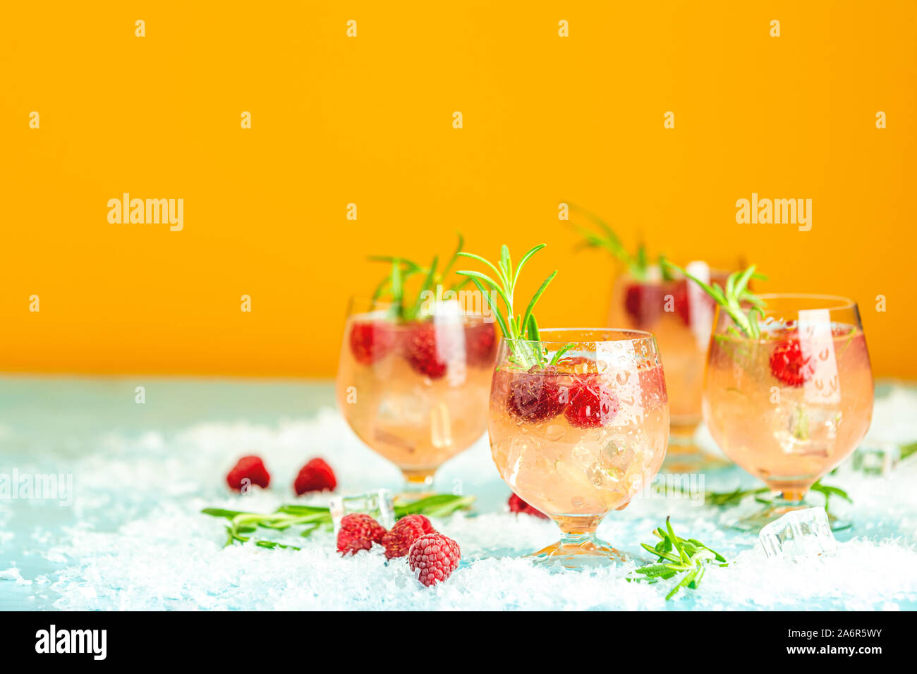 Fresh raspberry cocktail with rosemary and ice in glasses with water ...