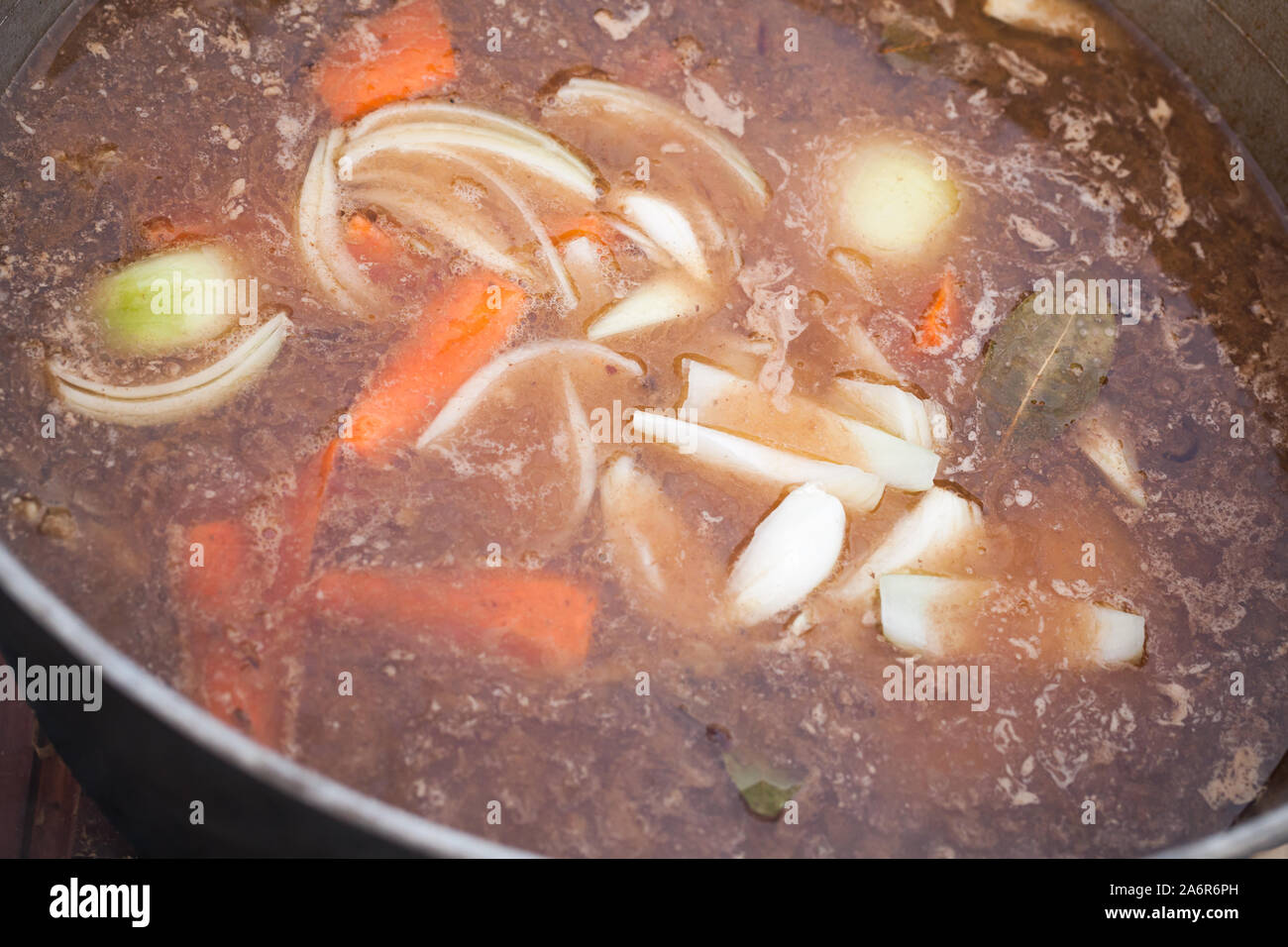 Spicy broth with beef and vegetables boil in a cauldron. Preparing of ...