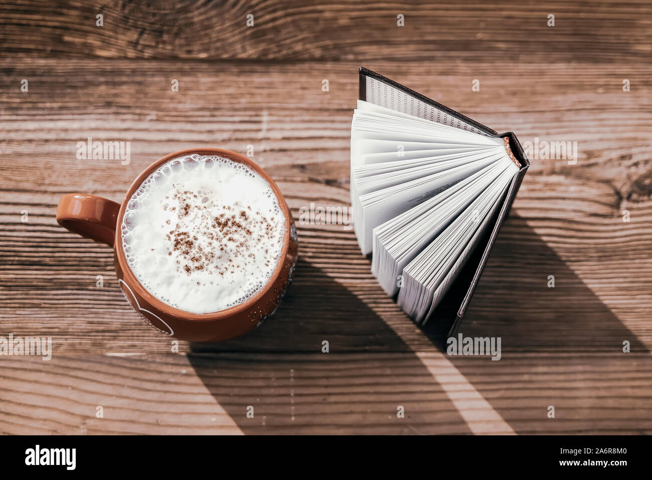 Coffee cup and open book on wooden table from the butt. Top view ...