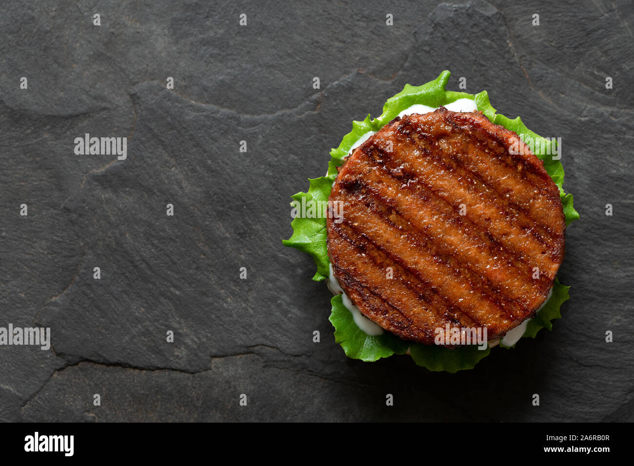 Freshly grilled plant based burger patty on bun with lettuce and sauce ...