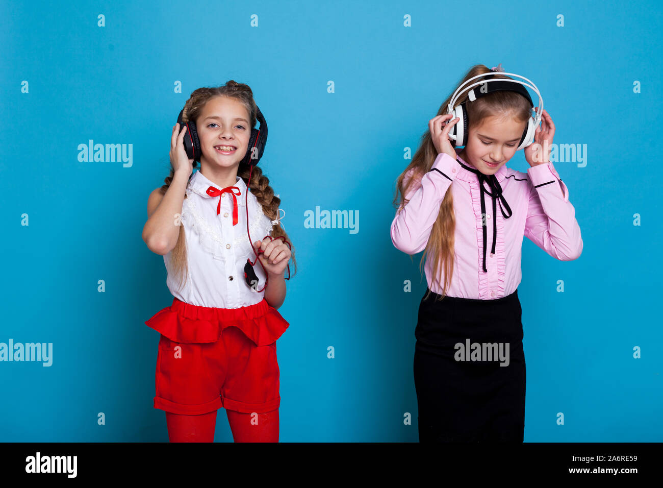 Two schoolgirl girls listen to music in big headphones Stock Photo - Alamy