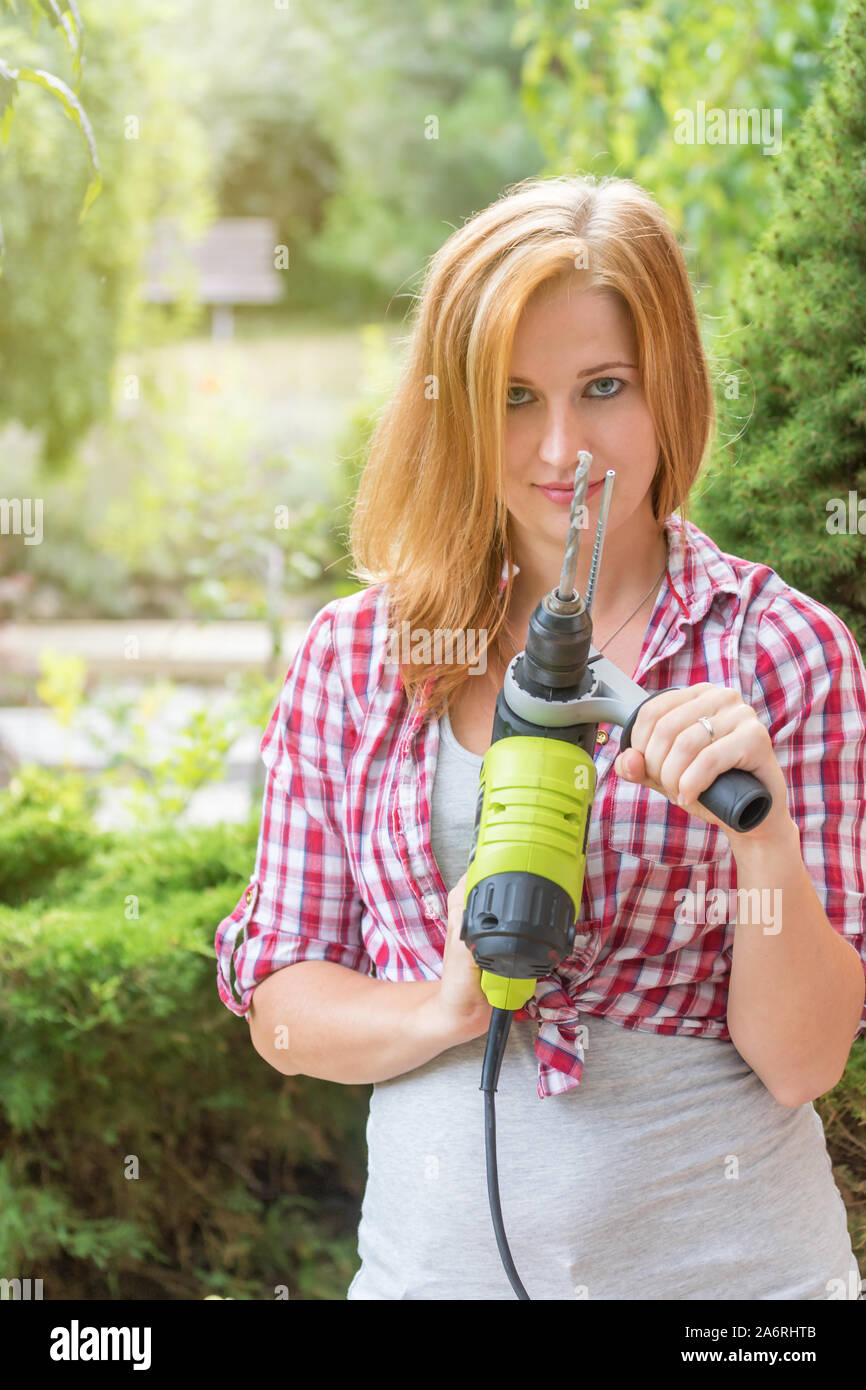 Attractive young woman clothed in checkered shirt is showing electric ...