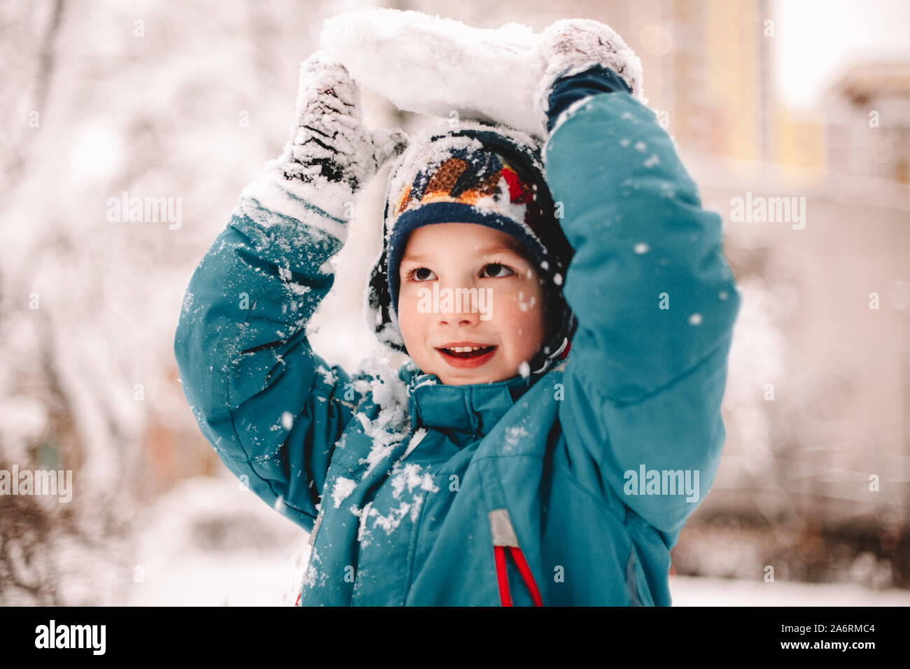 Playful boy holding chunk of snow above his head in winter Stock Photo ...