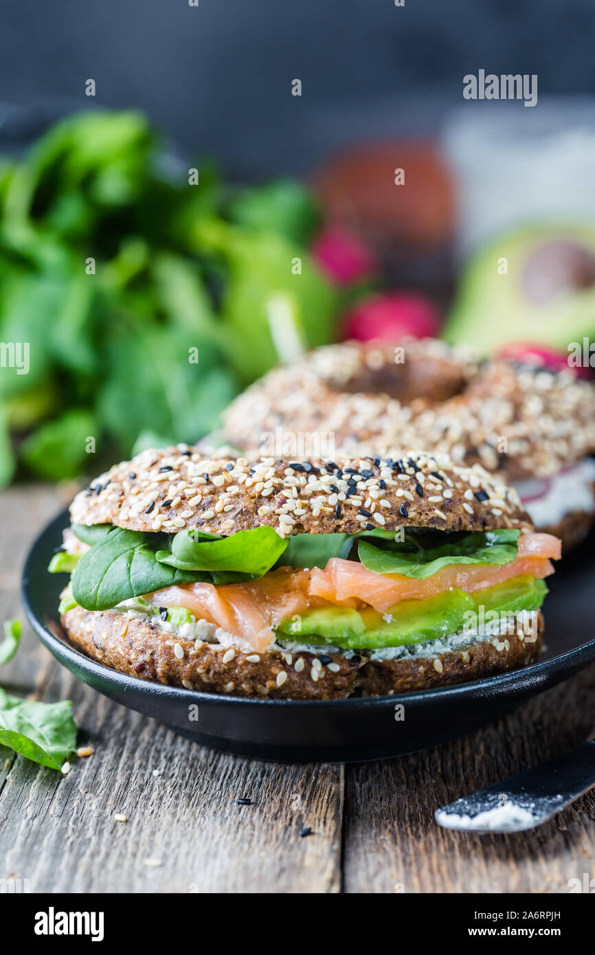 Bagels with cream cheese avocado, fish, arugula and radish on old ...