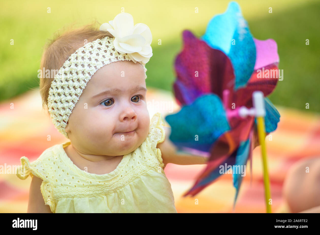 Baby playing with windmill toy in backyard on a blanket. Summer day ...