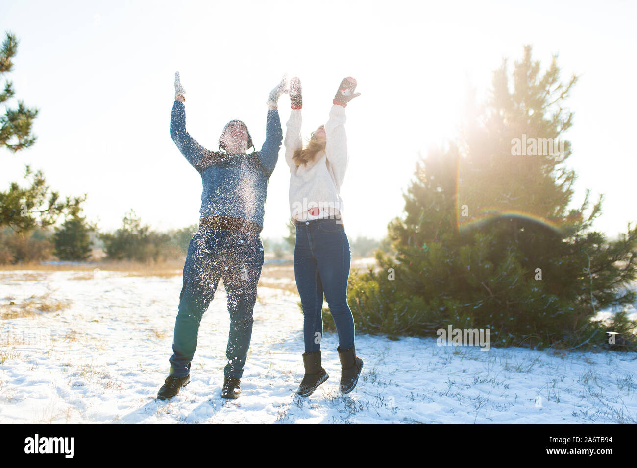 Loving couple play snowballs in winter in the forest. Throw each other ...
