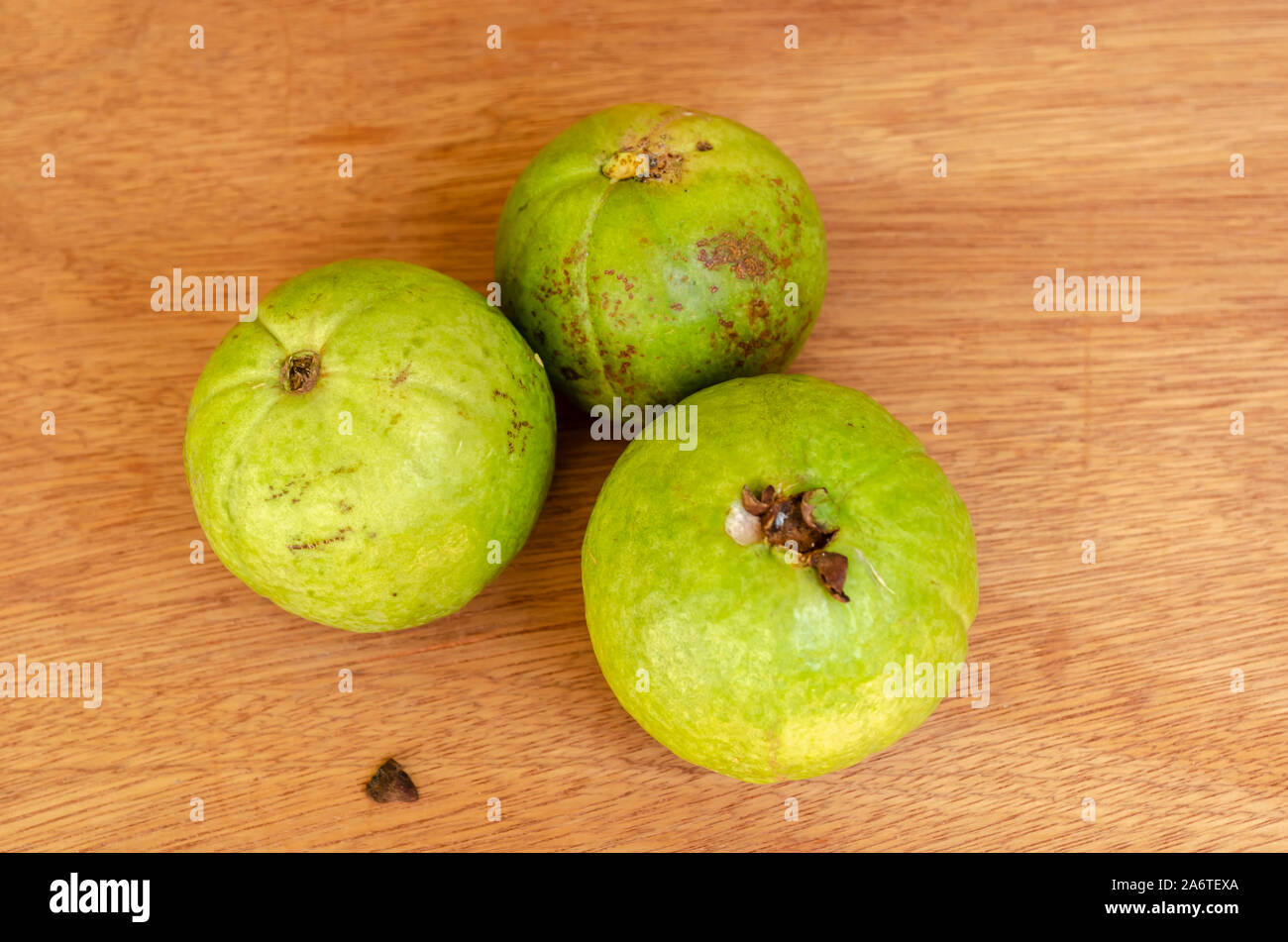 Three Round Guavas On Wooden Table Stock Photo - Alamy