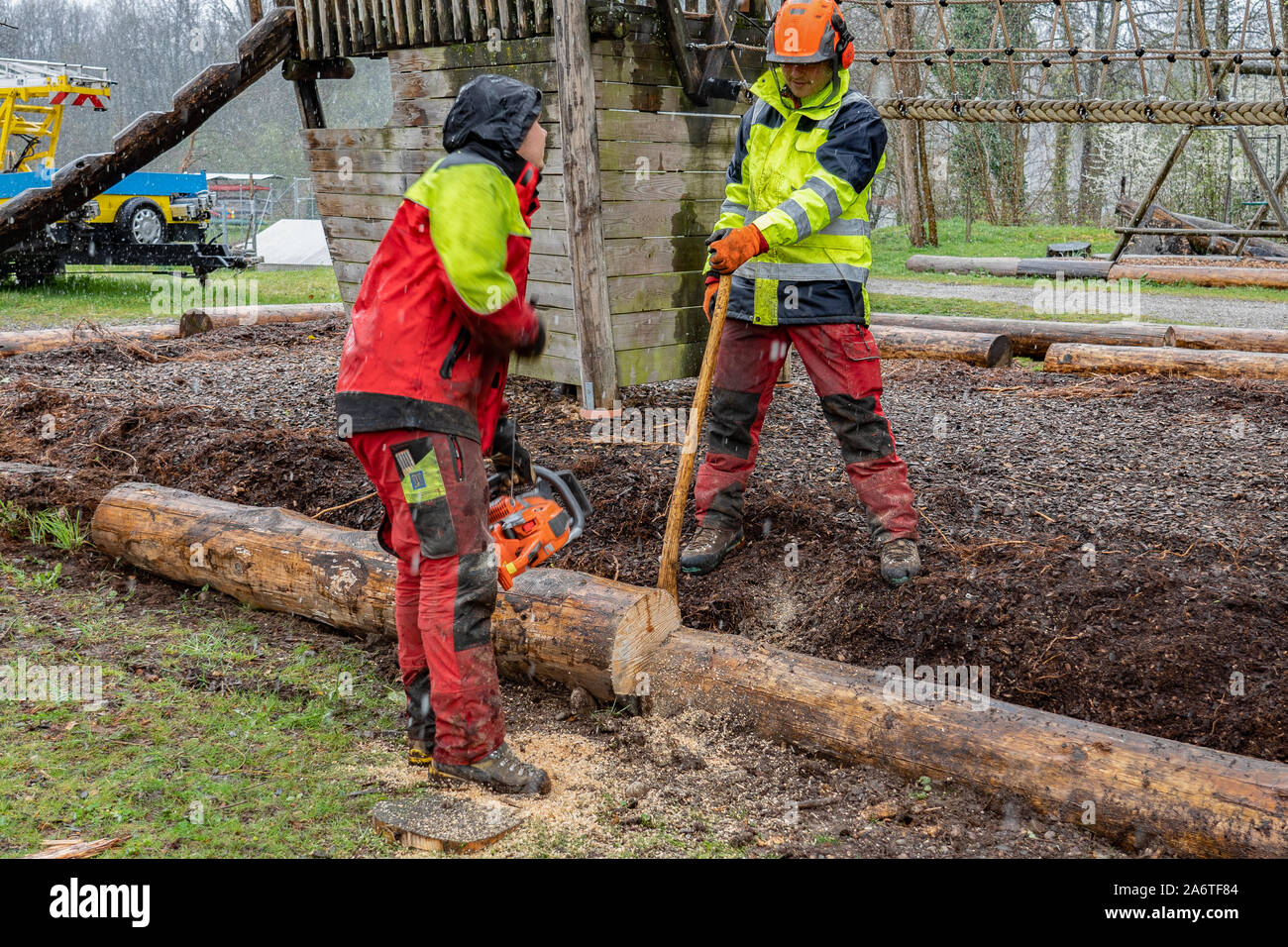 Young loggers working on a playground with tree house, cutting tree ...