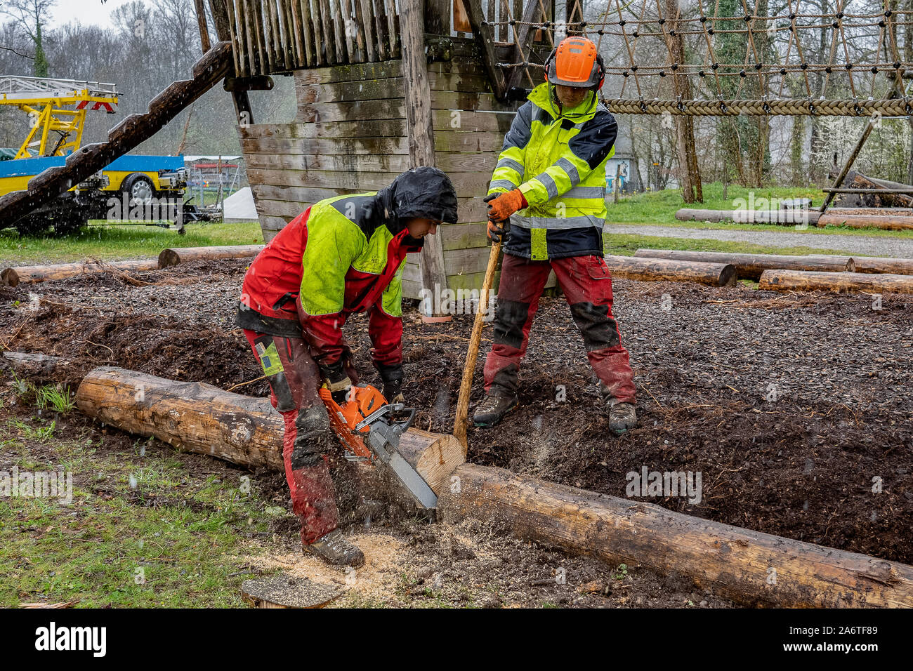 Young loggers working on a playground, cutting tree trunk with chain ...