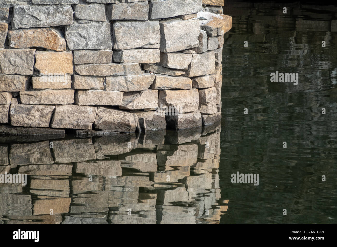Stonework of a bridge pylon with reflection in the water. Old stone ...