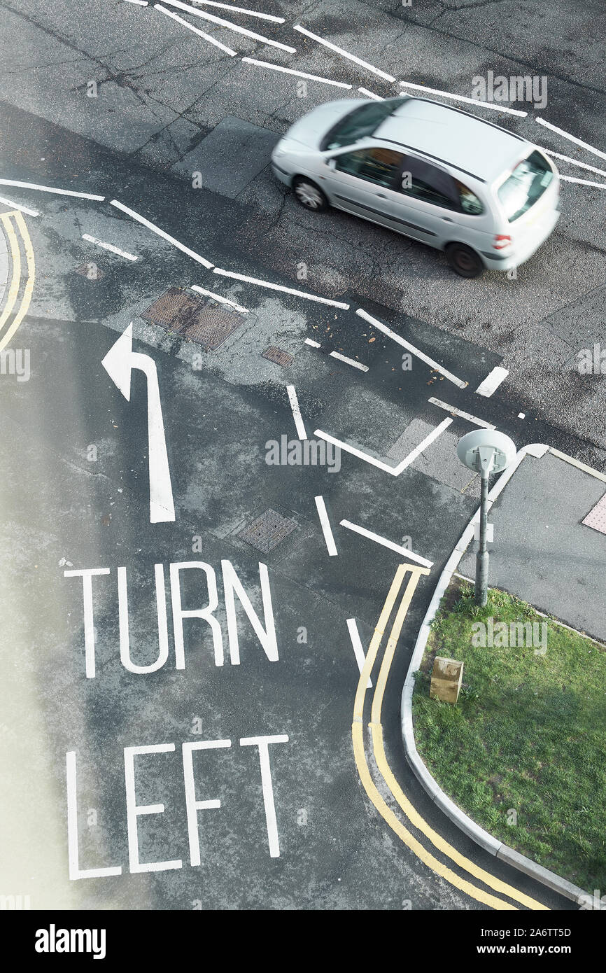 'Turn left' with an arrow sign painted in white on a minor road ...