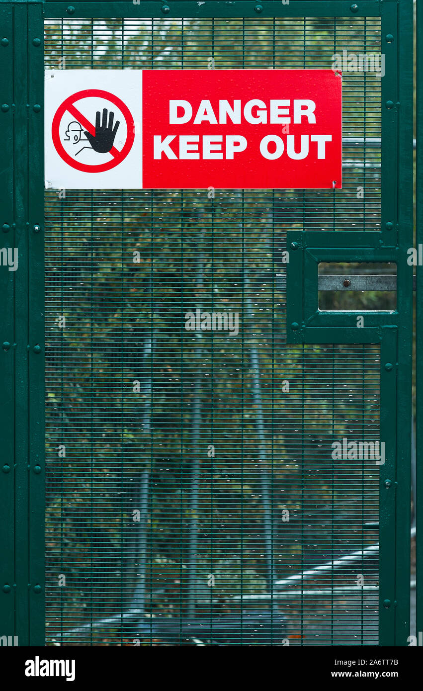 'Danger keep out' sign in unmissable red colour on a green iron gate ...