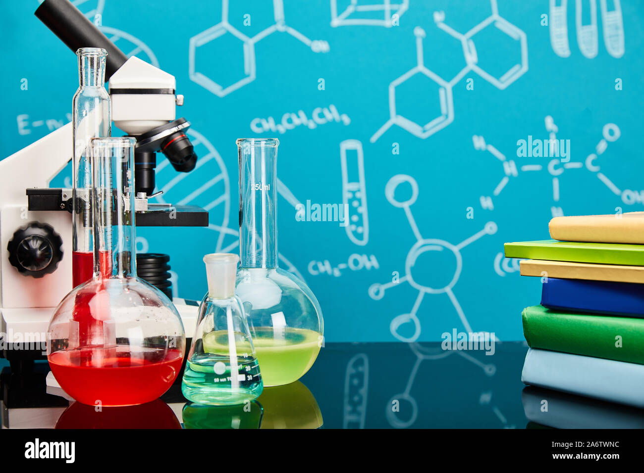 books, microscope, glass test tubes and flasks with colorful liquid on ...