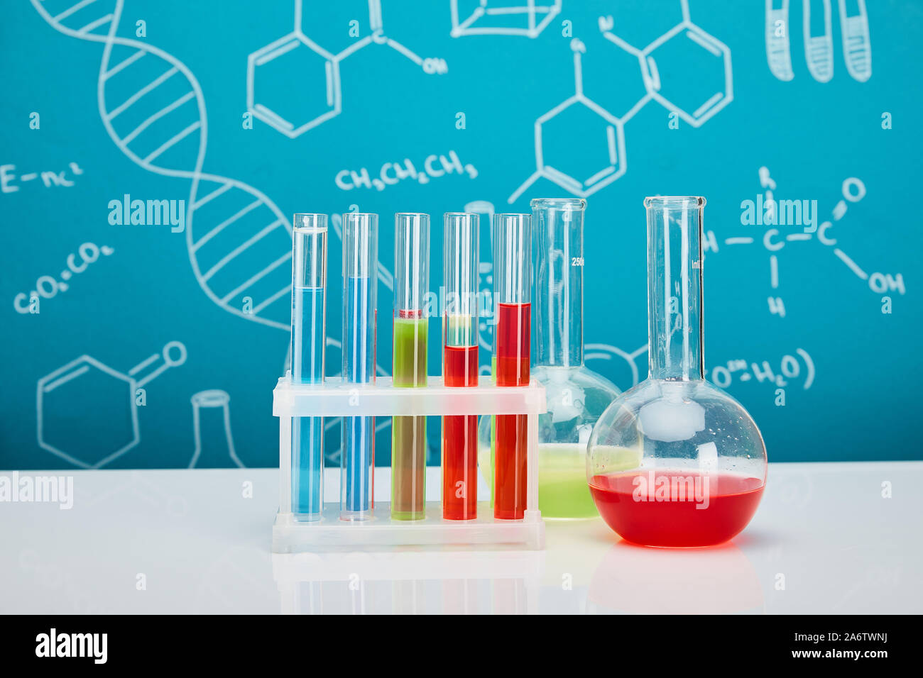 glass test tubes and flasks with colorful liquid on blue background ...