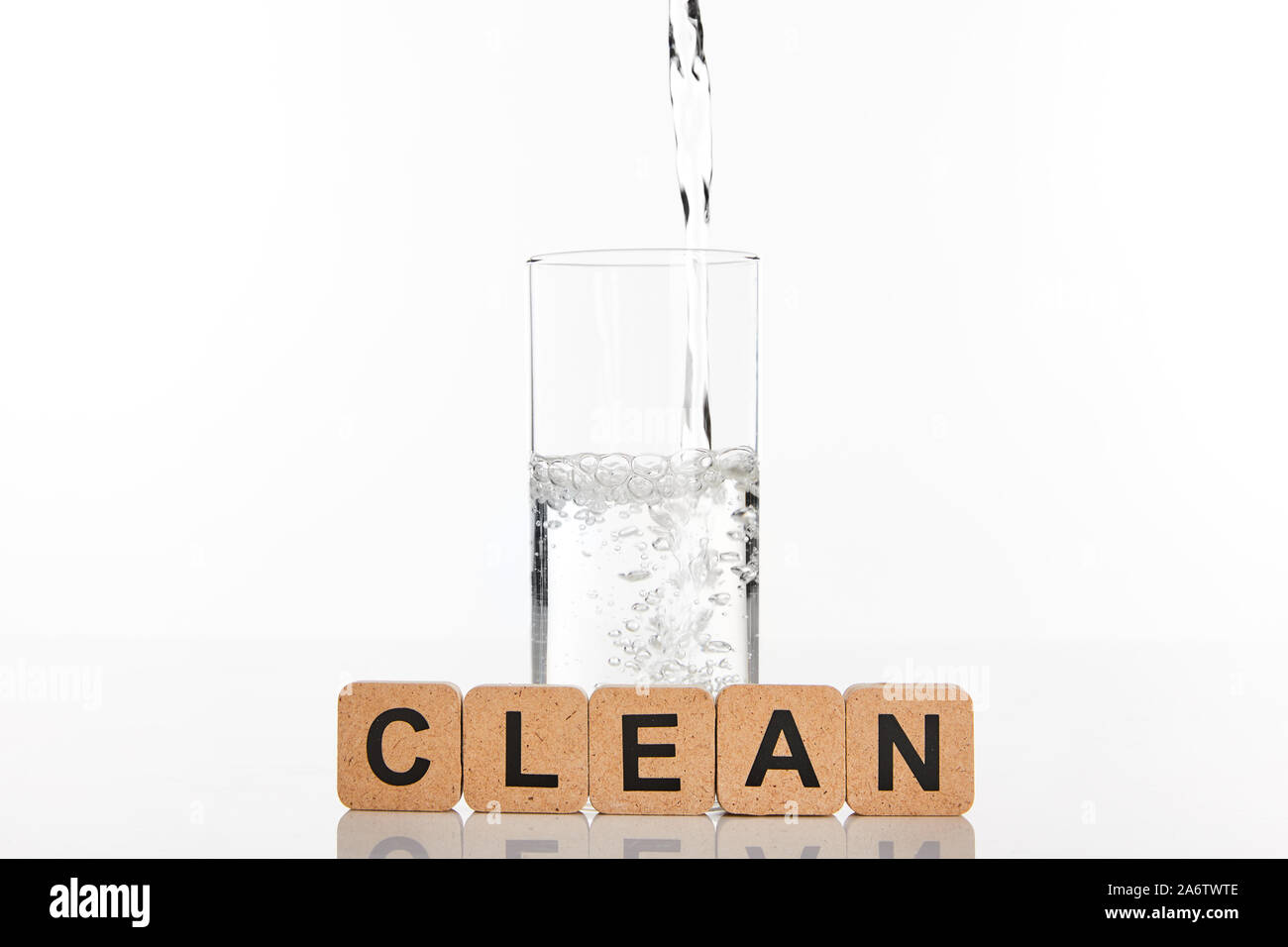 clear fresh water pouring in glass near cubes with clean lettering ...