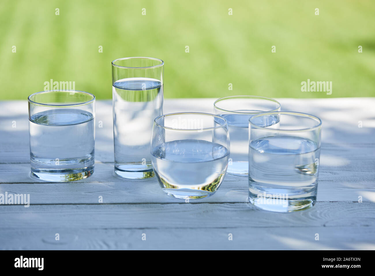 clear fresh water in transparent glasses in sunlight on wooden table ...