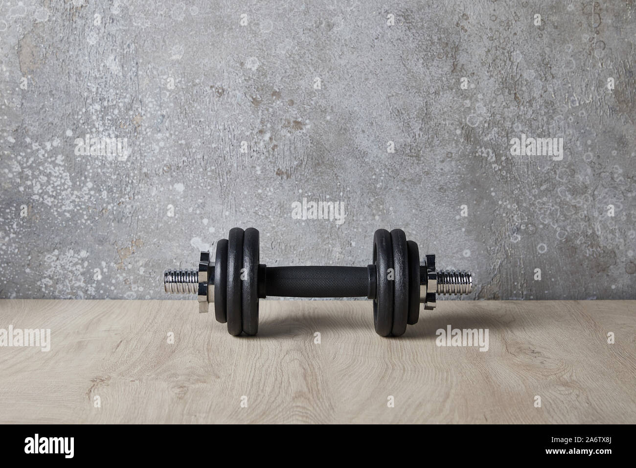 heavy and black dumbbell on wooden surface near concrete wall Stock ...