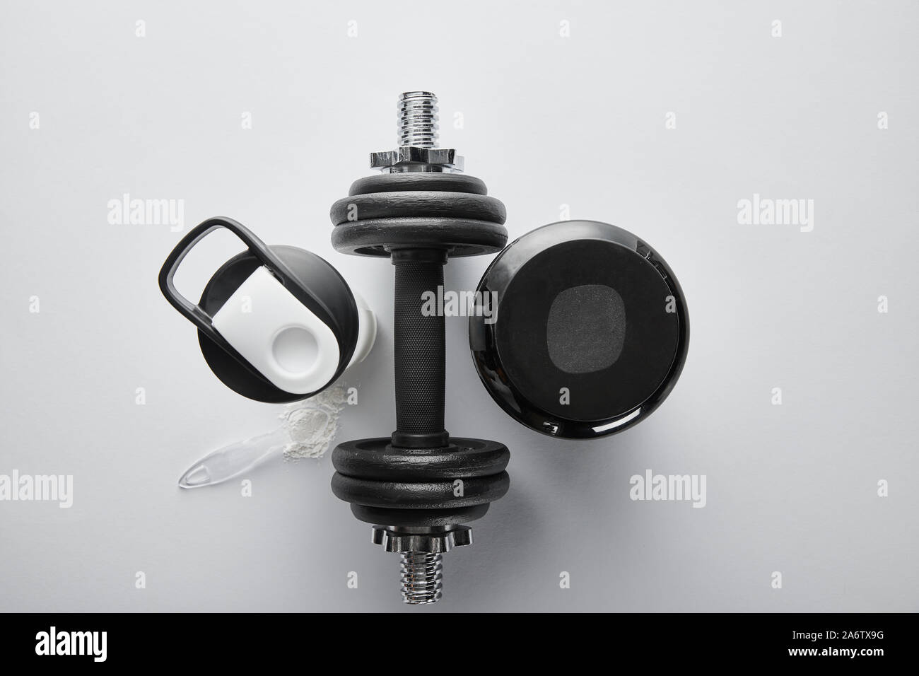 top view of spoon near protein, dumbbell and sports bottle on white ...