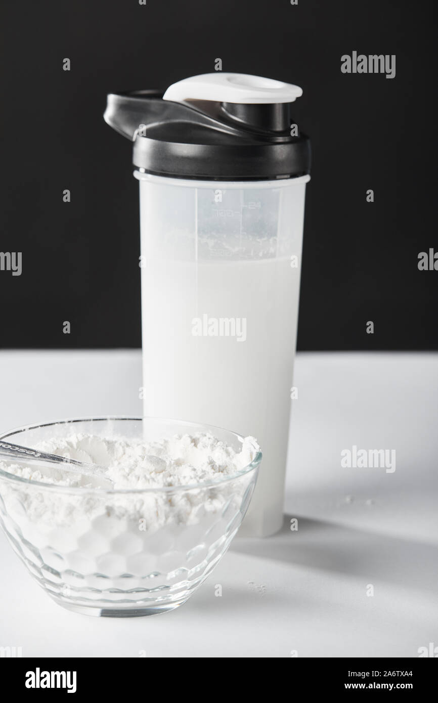 bowl with protein near sports bottle with protein shake on black Stock ...