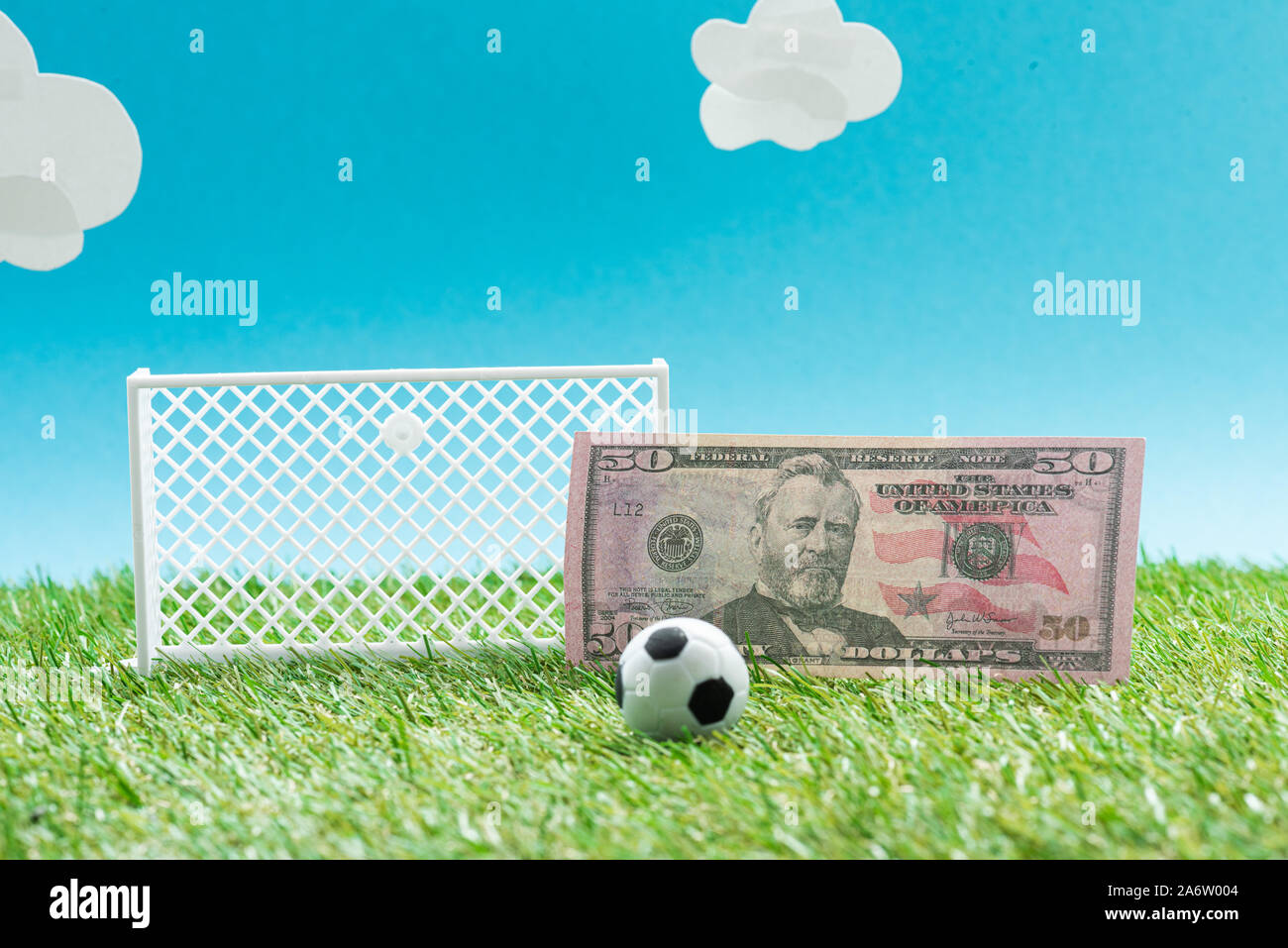 toy soccer ball and gates near dollar banknote on blue background with ...