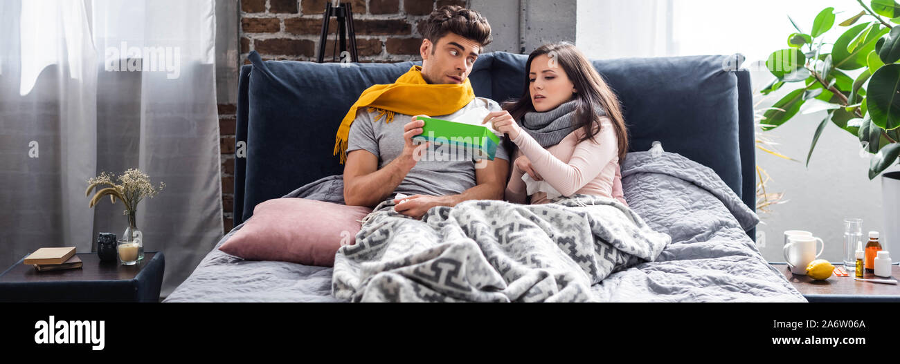 panoramic shot of sick girlfriend taking napkin and boyfriend holding ...