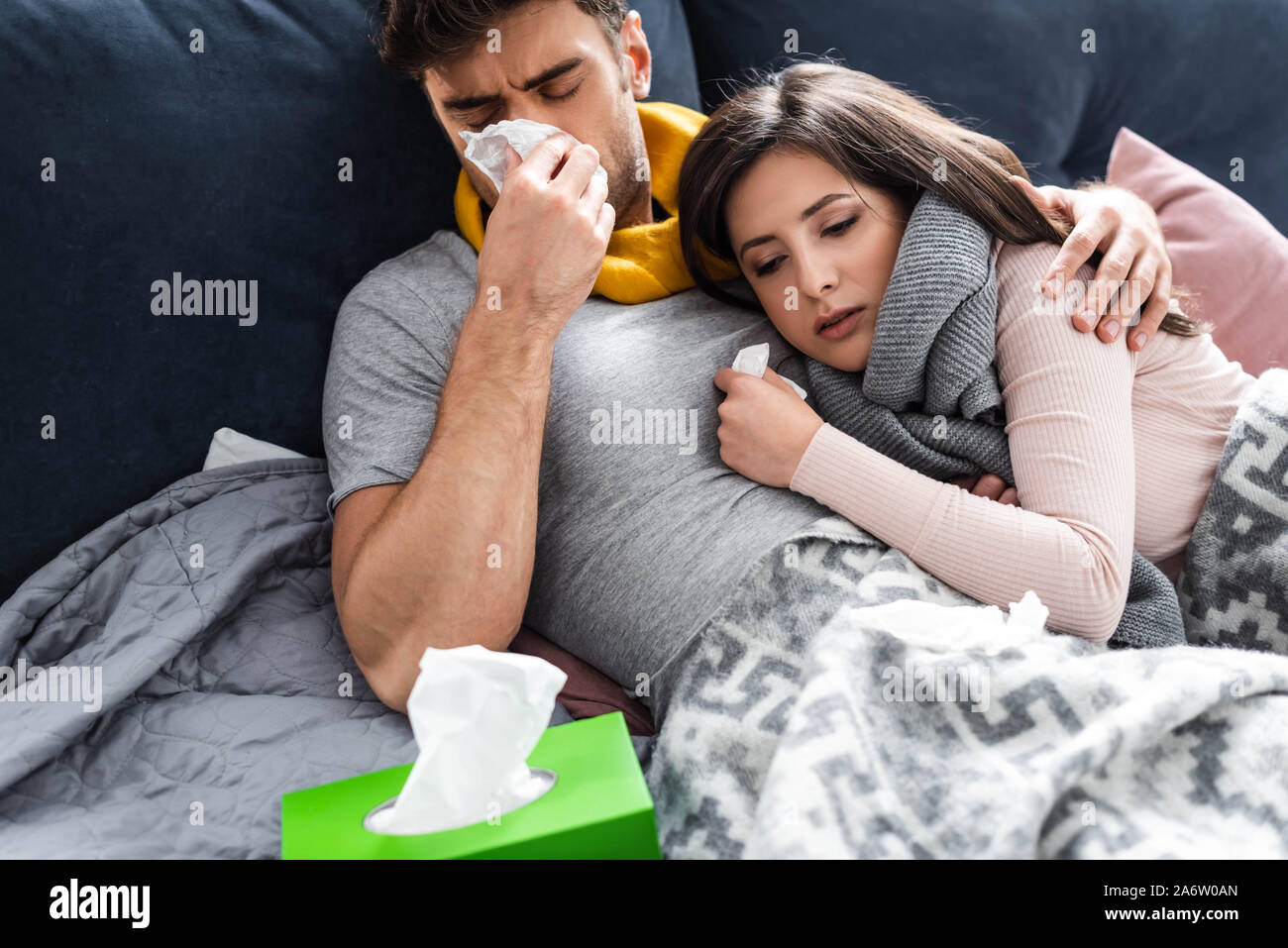 sick girlfriend and boyfriend sneezing and lying in bed Stock Photo - Alamy