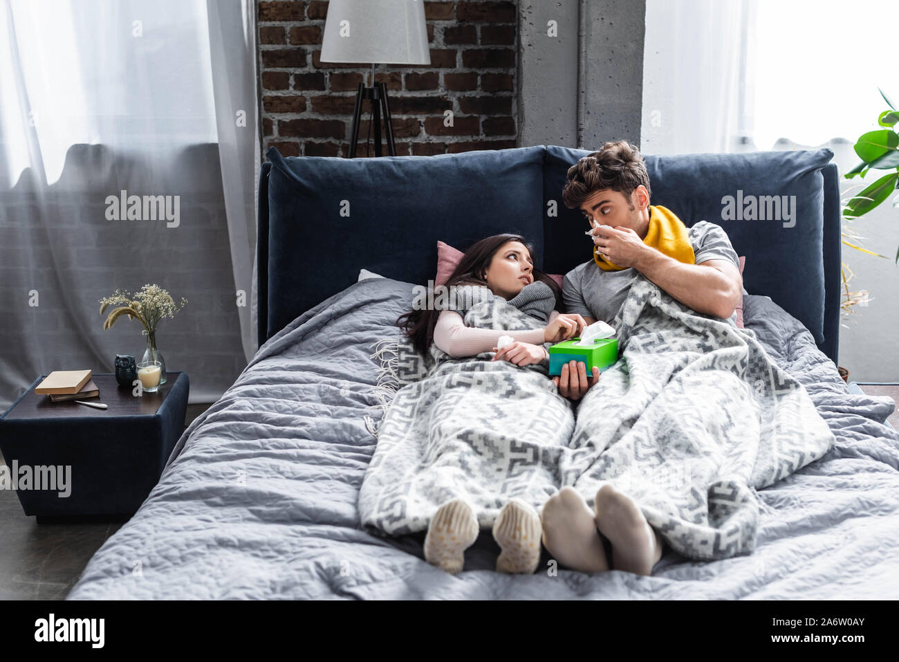 sick girlfriend and boyfriend sneezing and lying in bed Stock Photo - Alamy