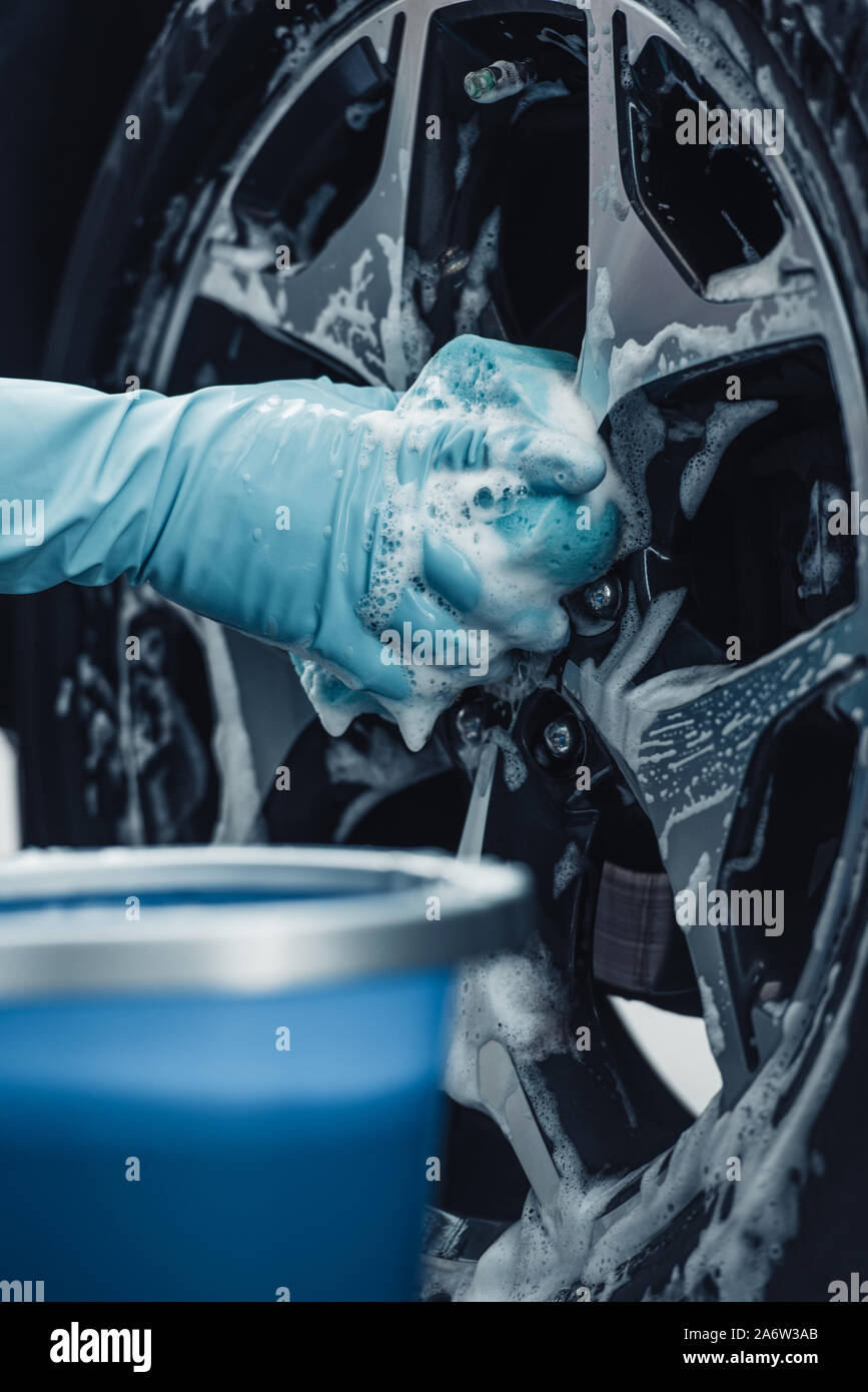 partial view of car cleaner washing wheel with sponge and detergent ...