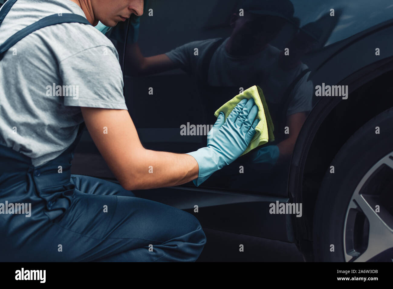 partial view of car cleaner polishing black car with rag Stock Photo ...