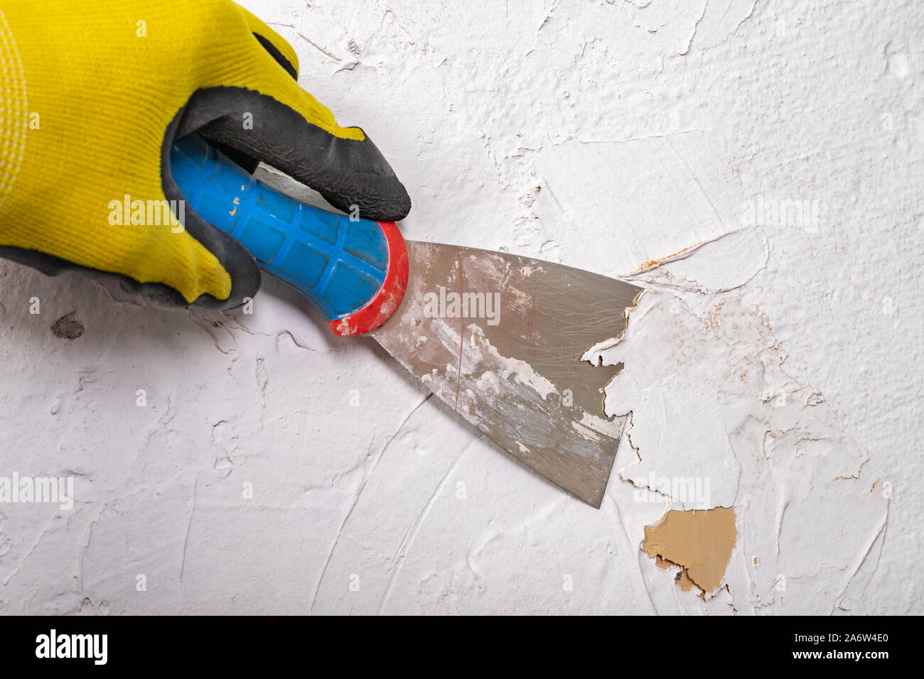 Removing old paint from the wall with a metal spatula. Small painting ...