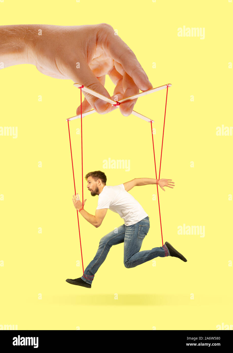 Man like a puppet in somebodies hands on yellow background. Concept of ...