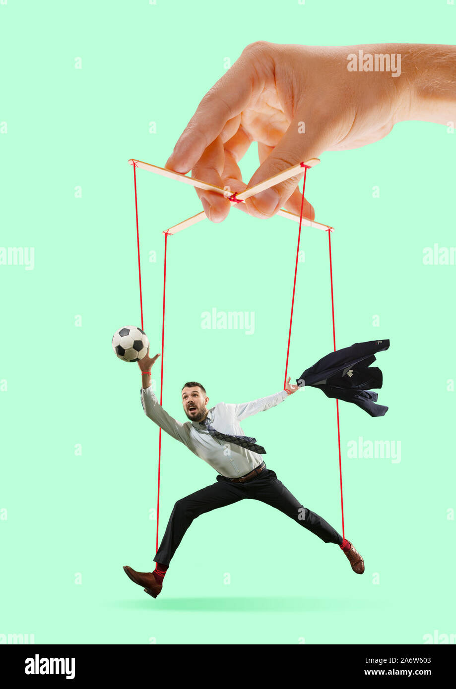 Man like a puppet in somebodies hands on green background. Concept of ...