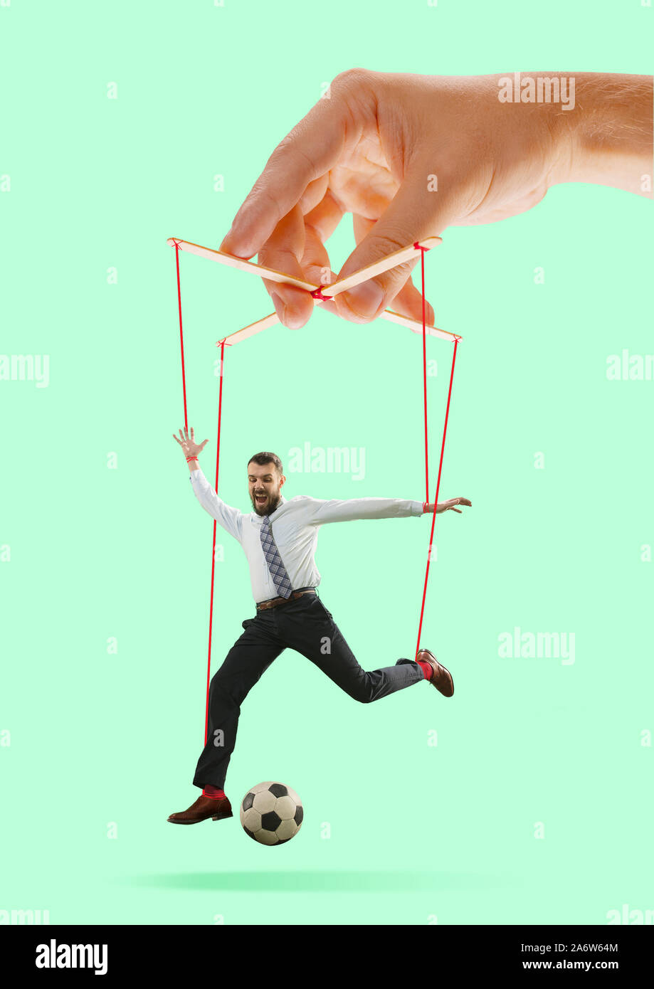Man like a puppet in somebodies hands on green background. Concept of ...
