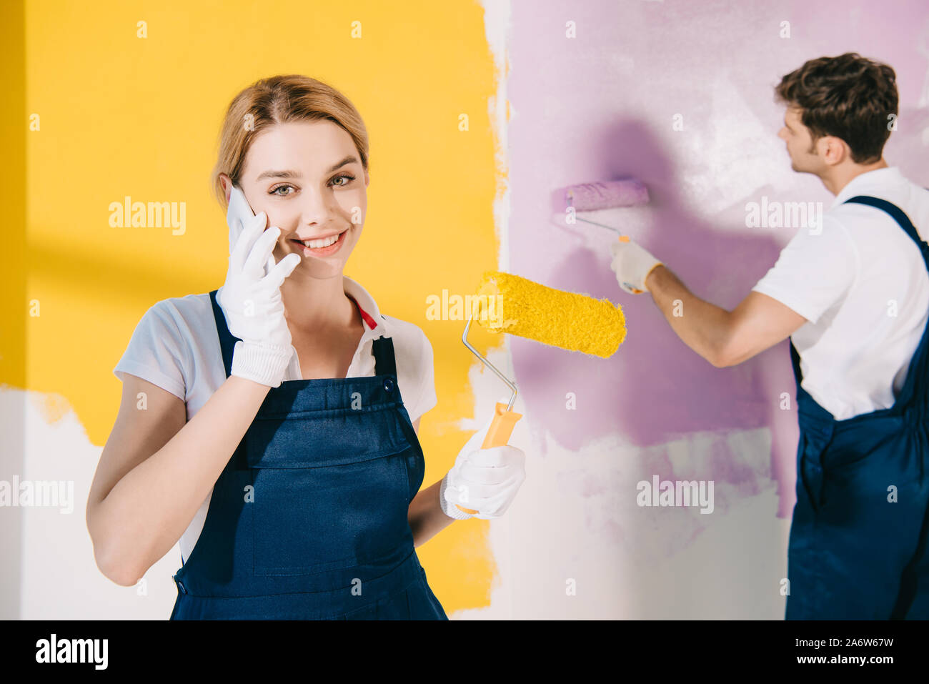 attractive painter in uniform talking on smartphone while handsome ...