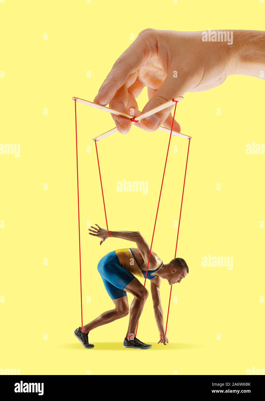 Man like a puppet in somebodies hands on yellow background. Concept of ...