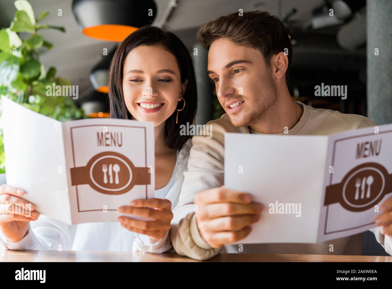 selective focus of man and happy woman looking at menus in restaurant ...