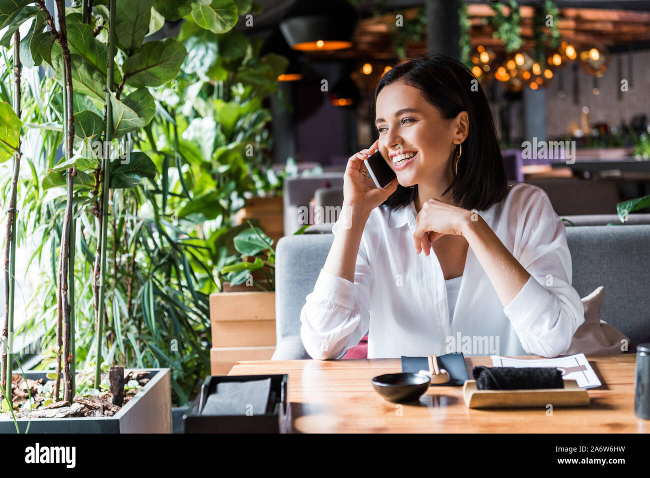 attractive woman smiling while talking on smartphone Stock Photo - Alamy