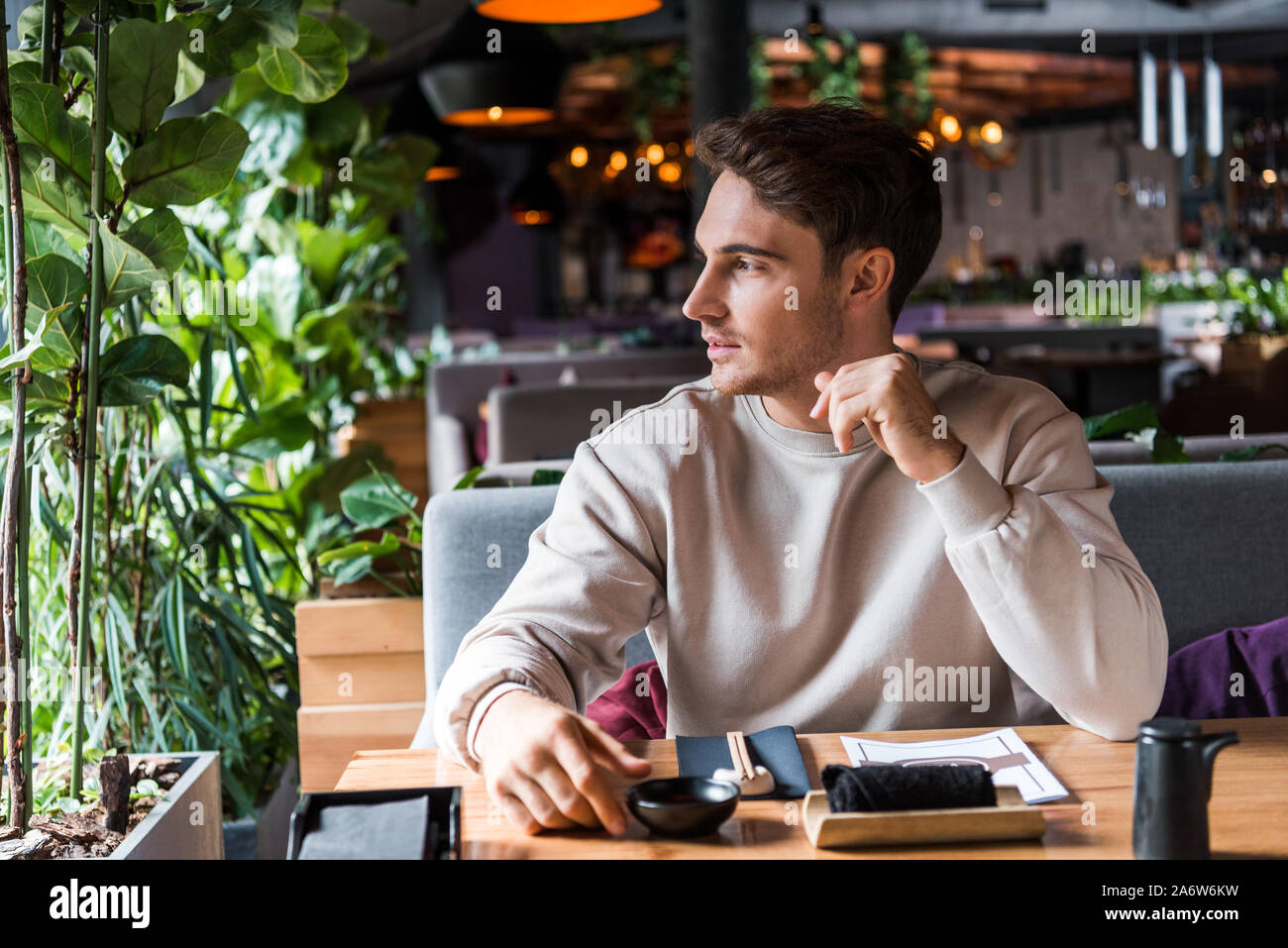 handsome man sitting in sushi bar near table with menu Stock Photo - Alamy