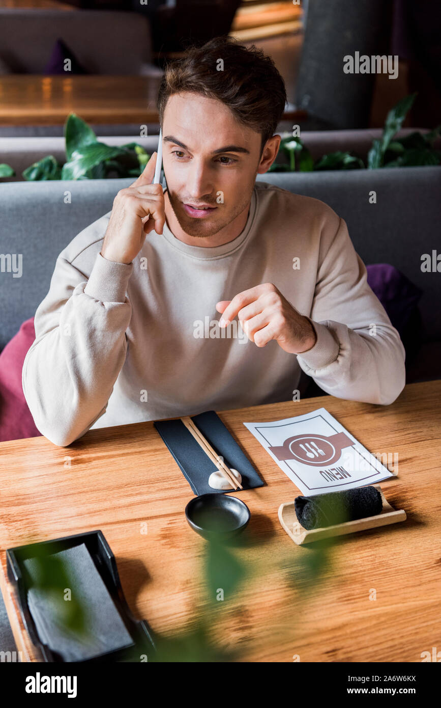 selective focus of handsome man talking on smartphone in sushi bar near ...