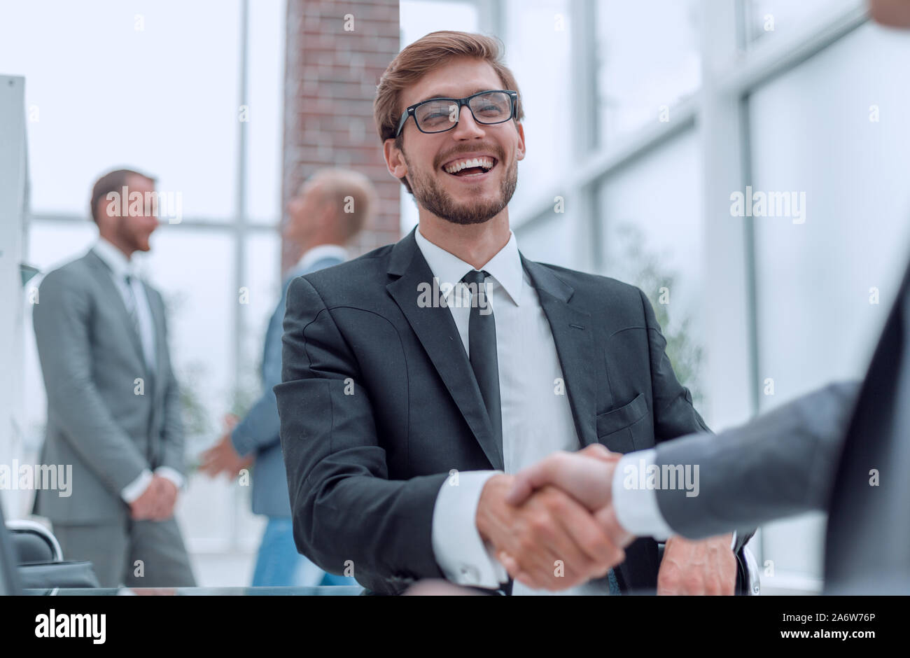 happy business partners shaking hands at the negotiating table ...