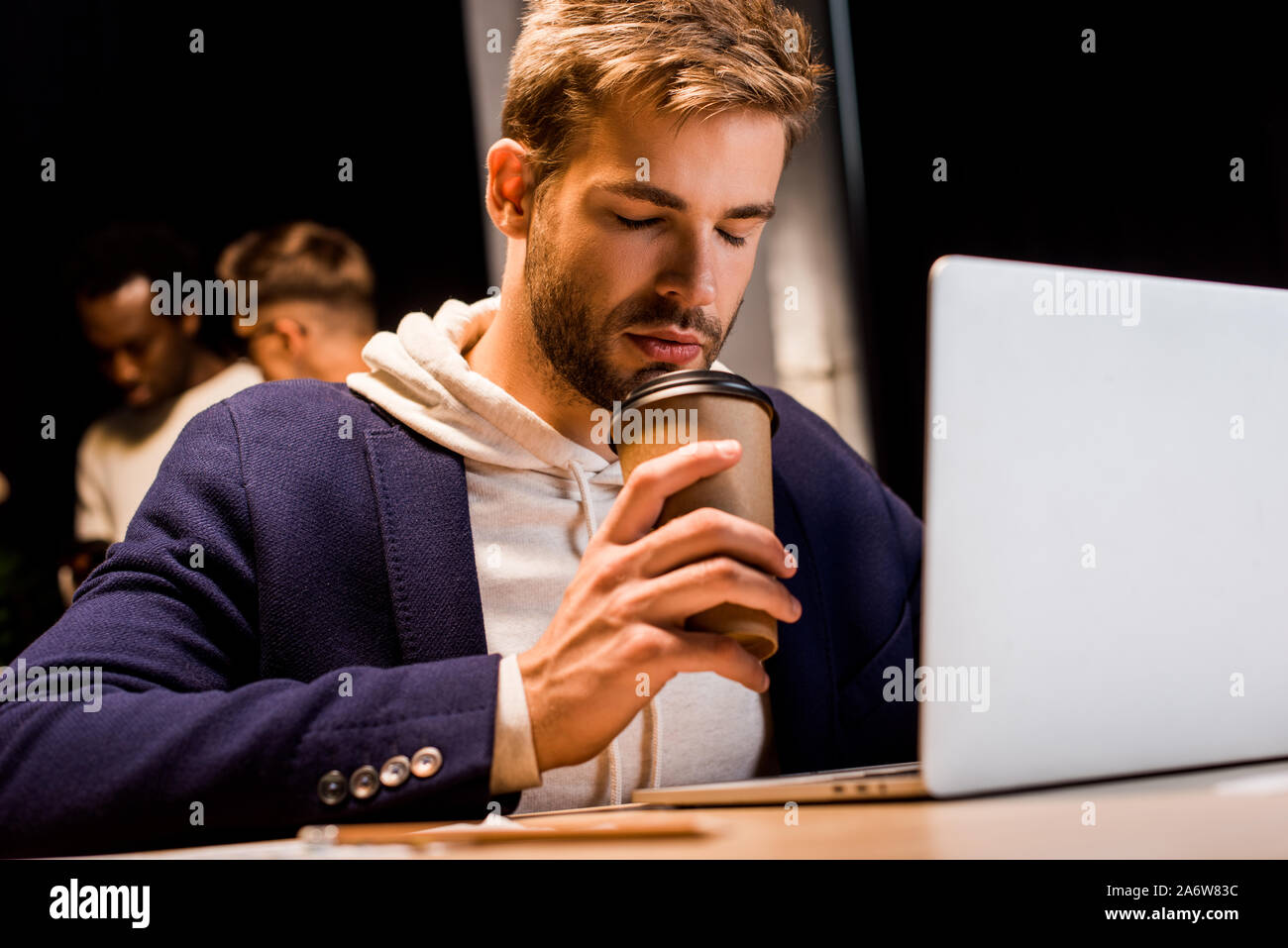 exhausted businessman drinking coffee to go while working at night in ...