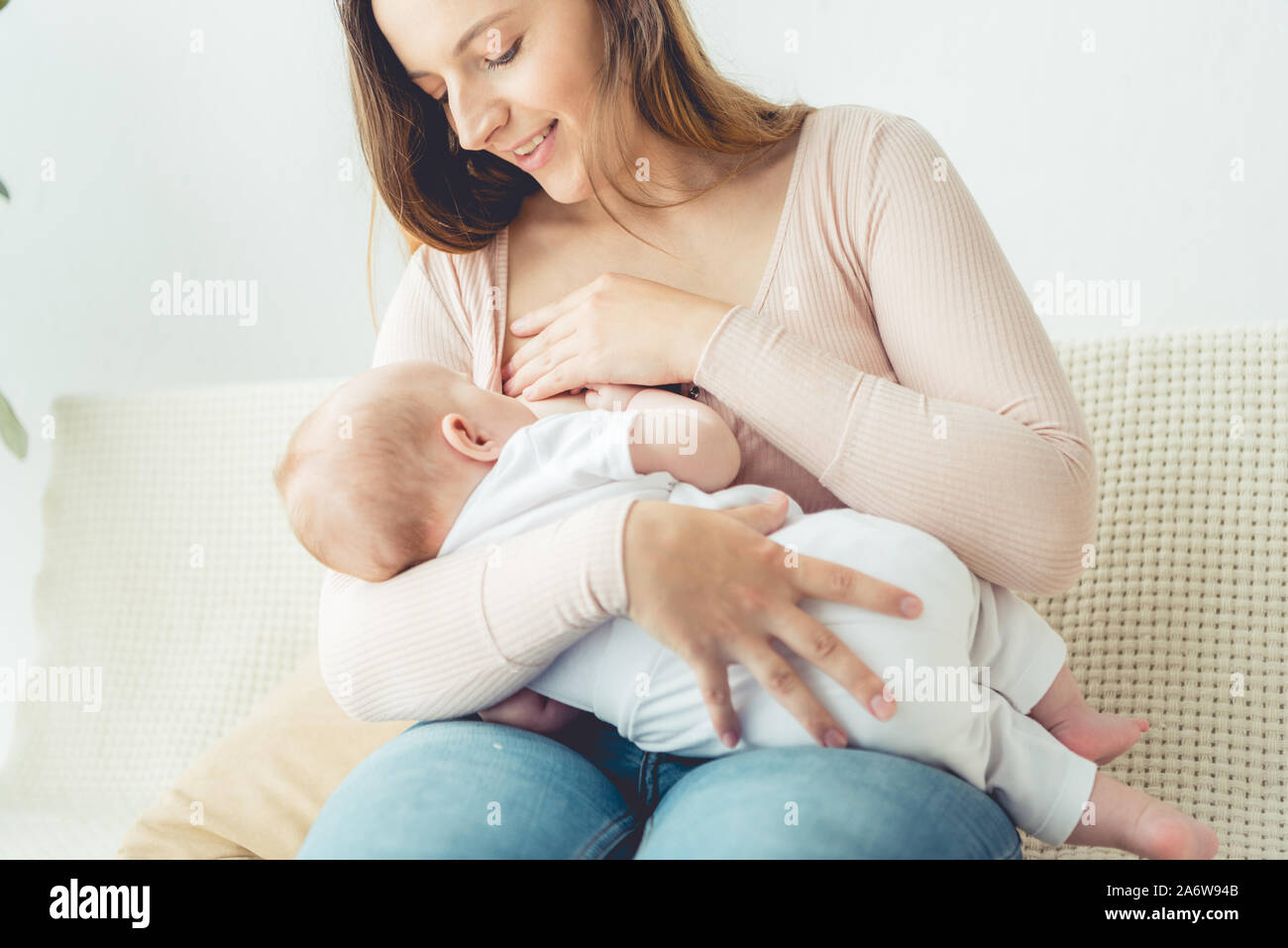attractive and smiling mother breastfeeding her child in apartment Stock Photo - Alamy