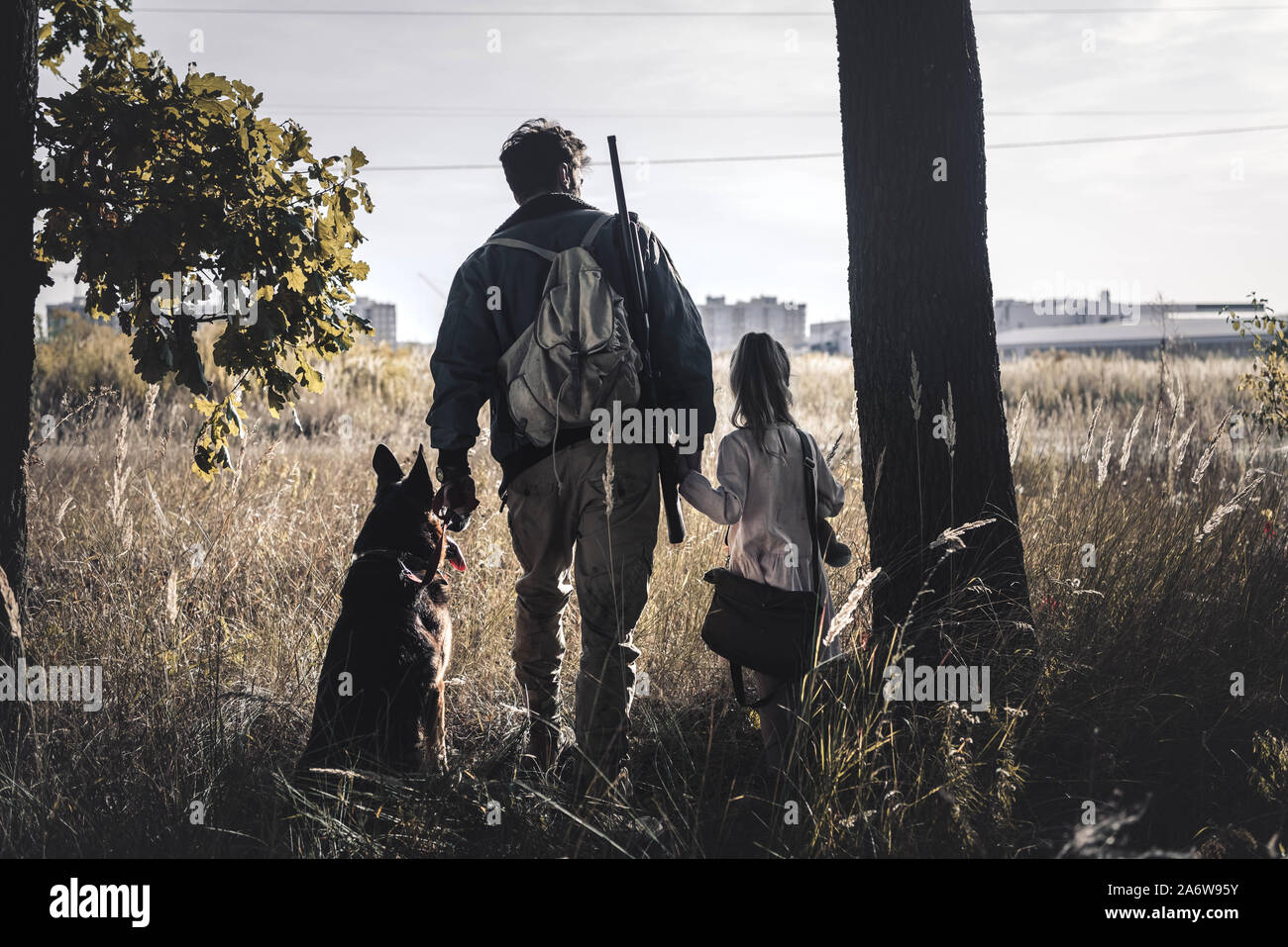 back view man standing in field with kid and german shepherd dog, post ...
