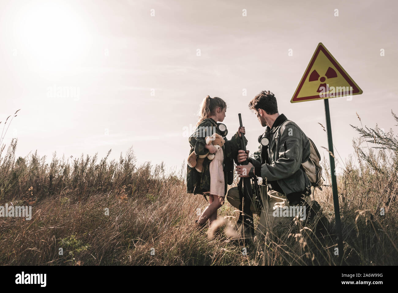 handsome man with gun near kid with teddy bear and toxic symbol, post ...