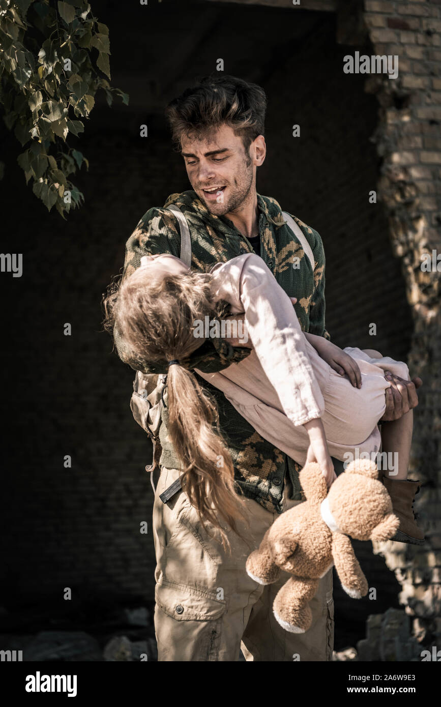 upset man holding in arms kid with teddy bear, post apocalyptic concept Stock Photo - Alamy