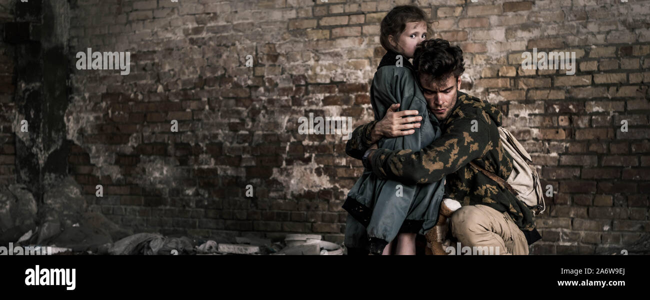 panoramic shot of handsome man hugging child near brick wall, post ...