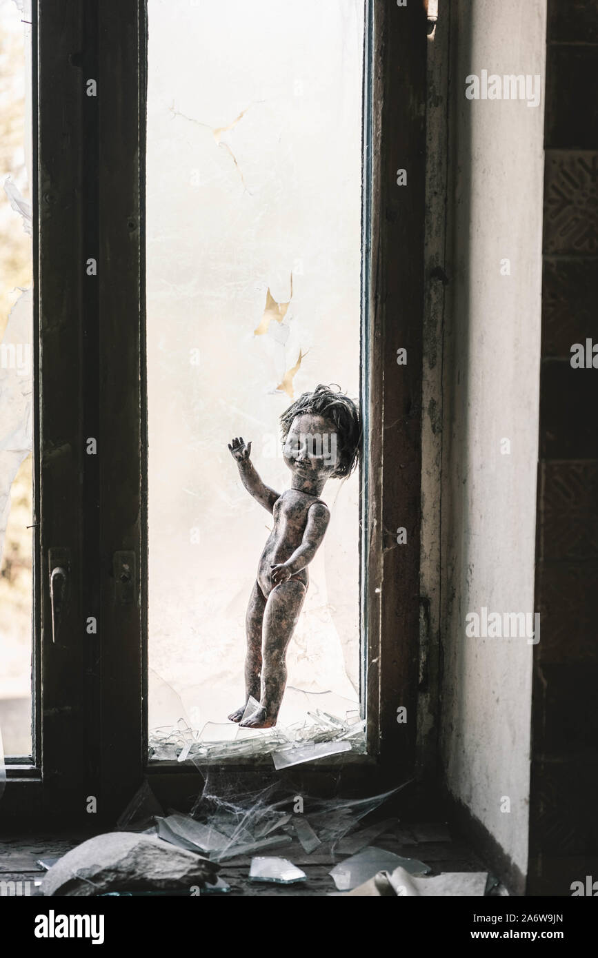 burnt baby doll near broken window and glass, post apocalyptic concept ...