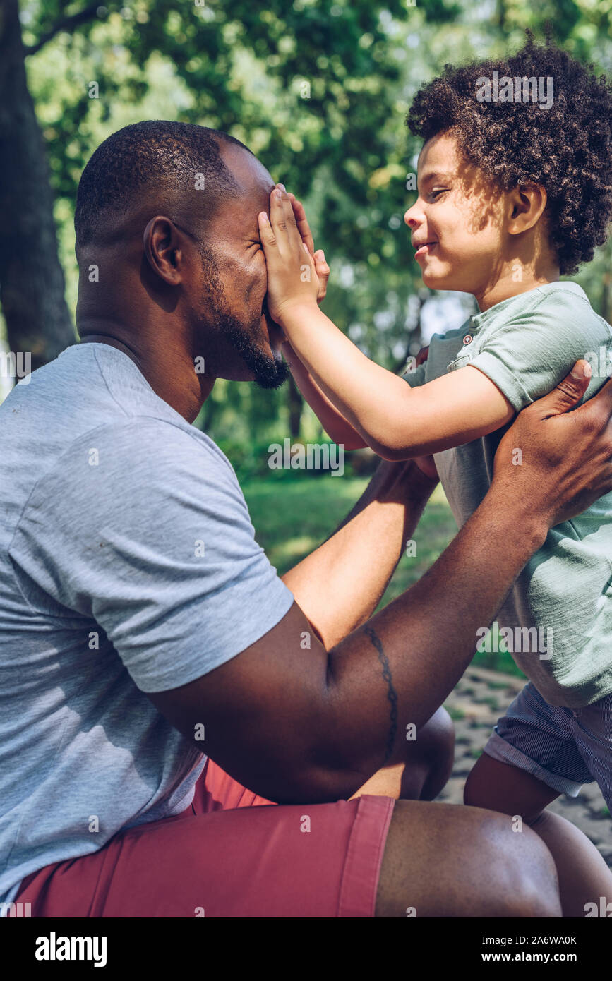 cute african american boy closing fathers eyes with hands while having ...