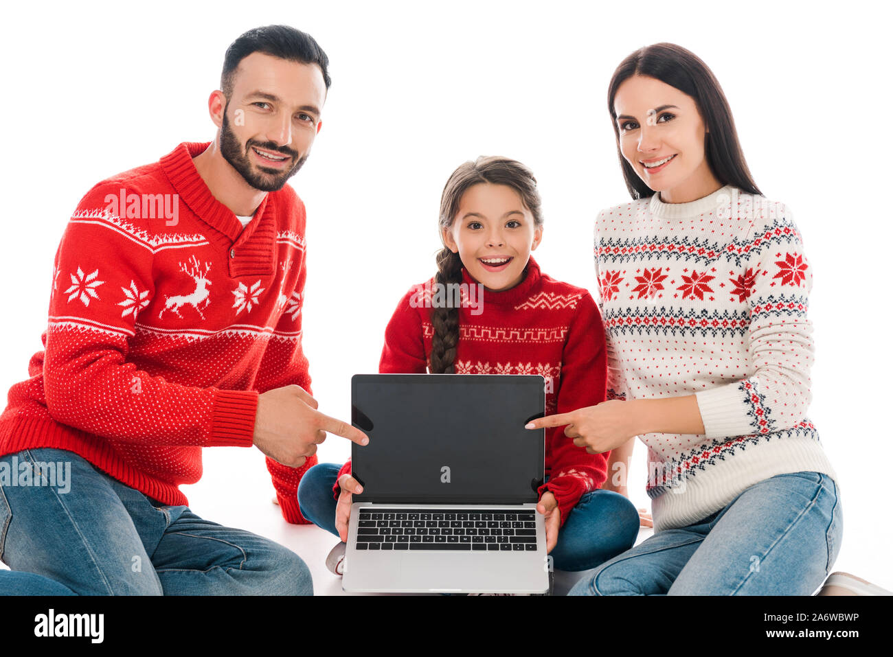 happy parents pointing with finger at laptop with blank screen near ...