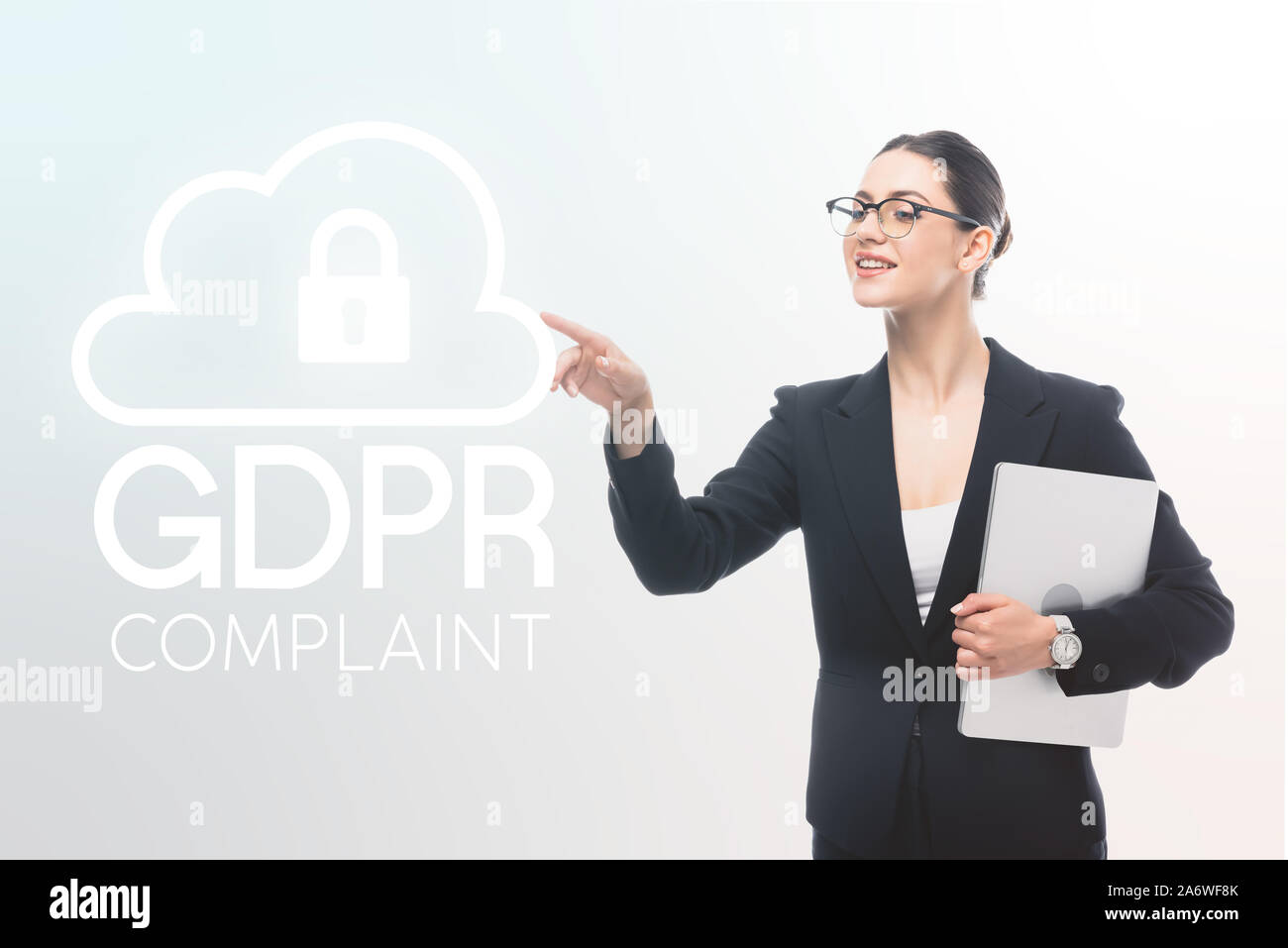 attractive businesswoman holding laptop and pointing with finger at ...